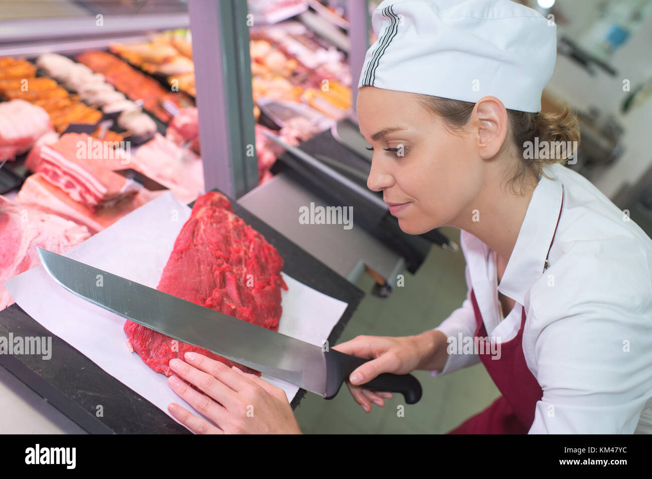 happy female butcher cutting meat at butchery counter Stock Photo - Alamy