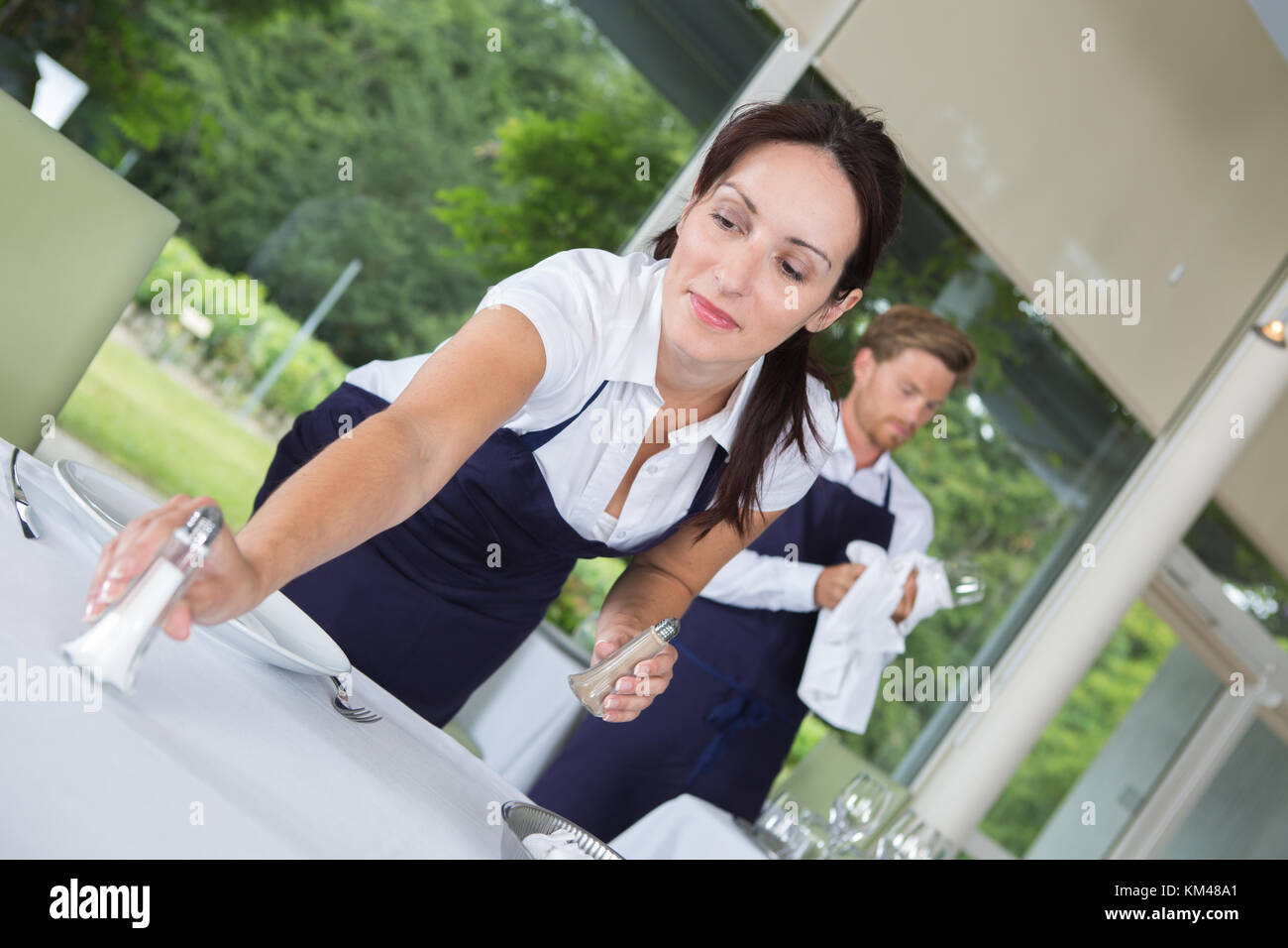 smiling waitress setting the table in a restaurant Stock Photo - Alamy
