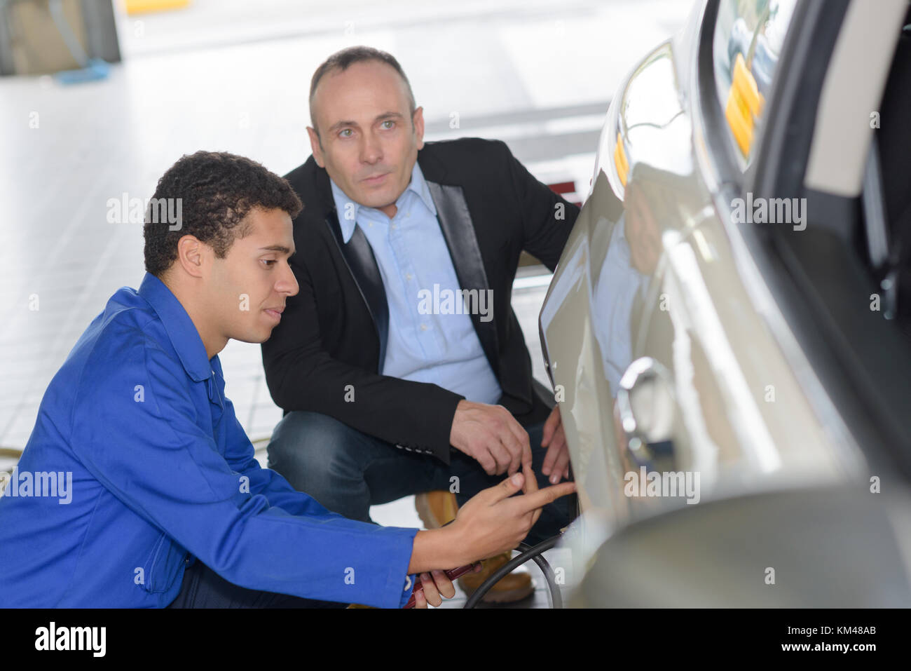 young mechanic talking to male client Stock Photo - Alamy