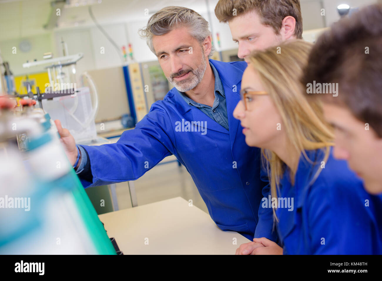 Teacher with students, wearing blue jackets Stock Photo - Alamy