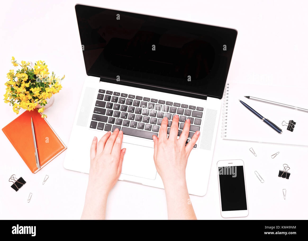 Workspace with female hands on laptop keyboard, mobile phone and ...