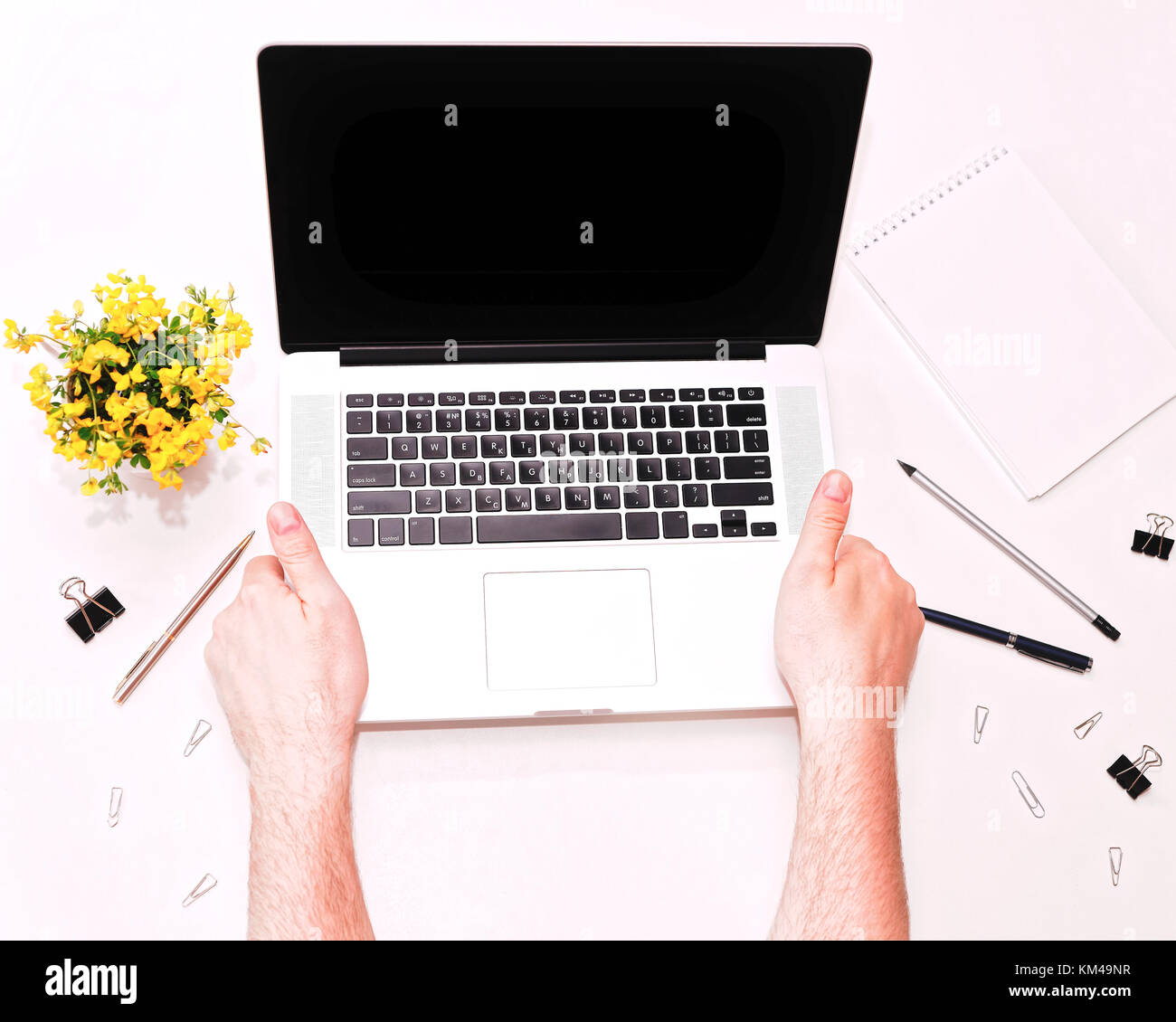 Woman hands holding laptop. Workspace with diary, and flowers on the ...