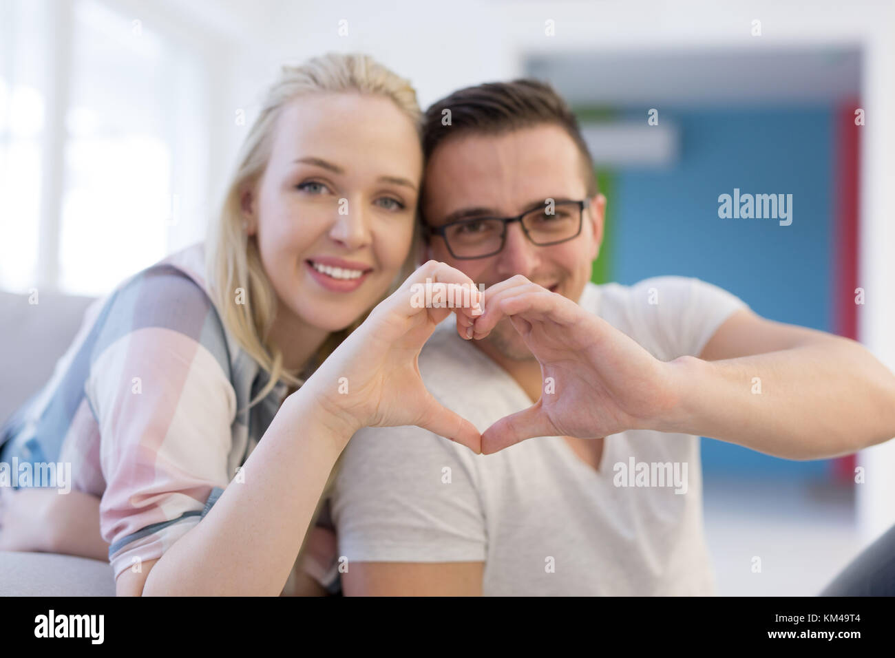 Young lovely couple making heart with hands at home Stock Photo - Alamy