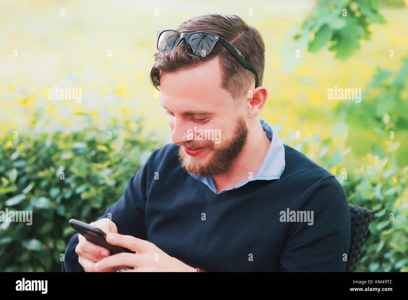 Smiling young man sending messages via his mobile phone Stock Photo - Alamy