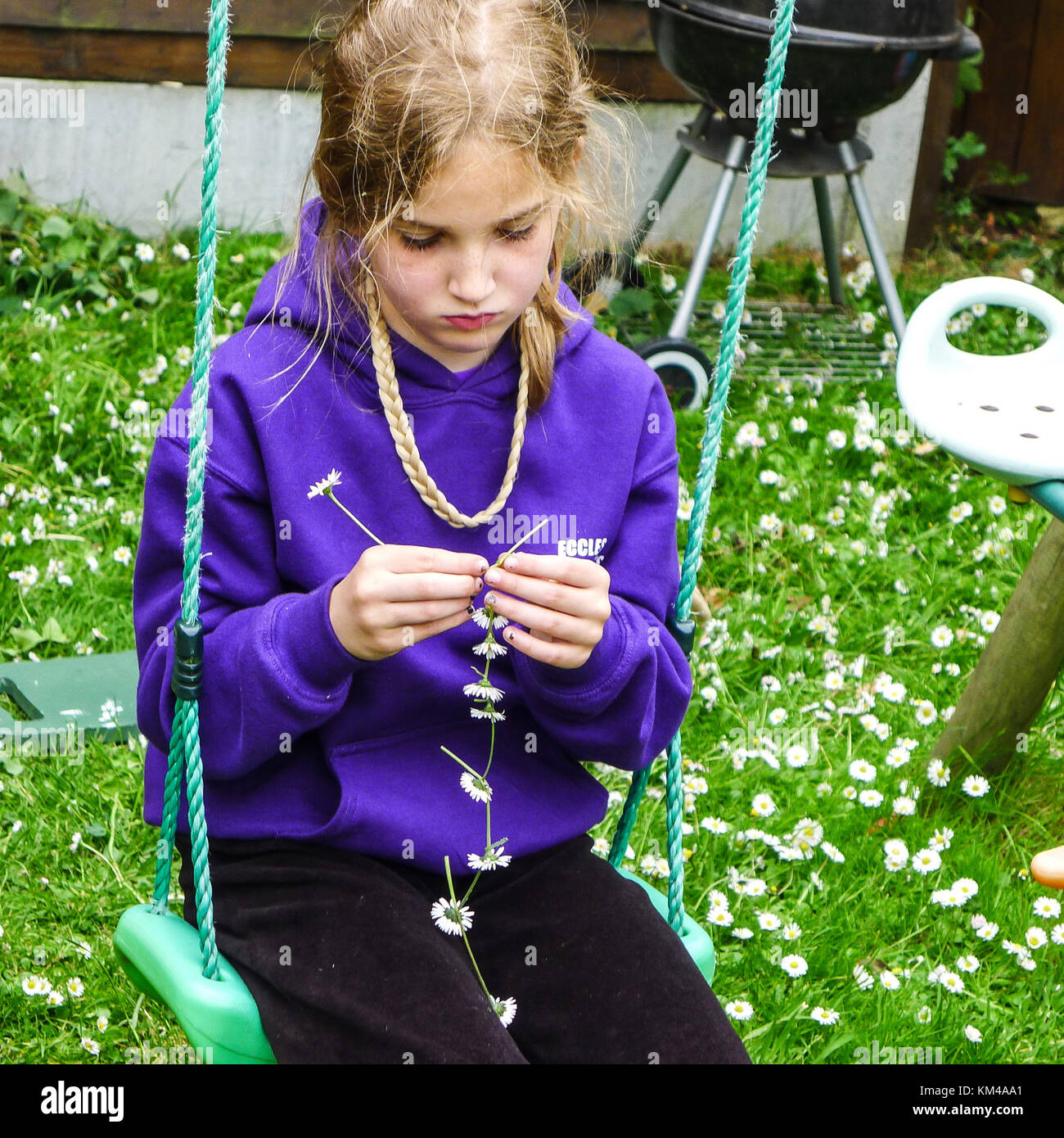 Child sitting on a swing in the garden making a daisy chain, Dublin ...