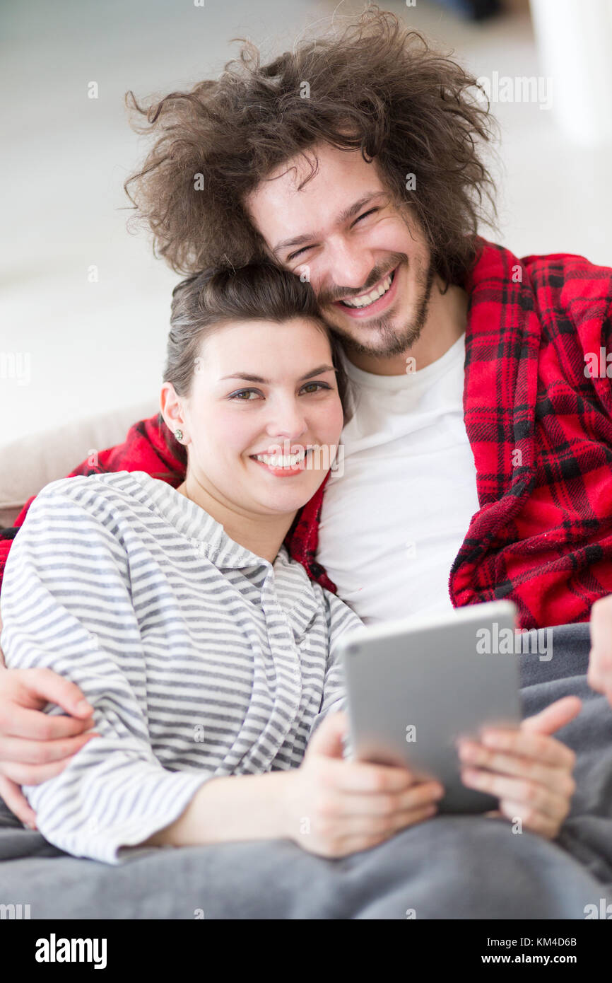 Young couple relaxing at home using tablet computers reading in the ...
