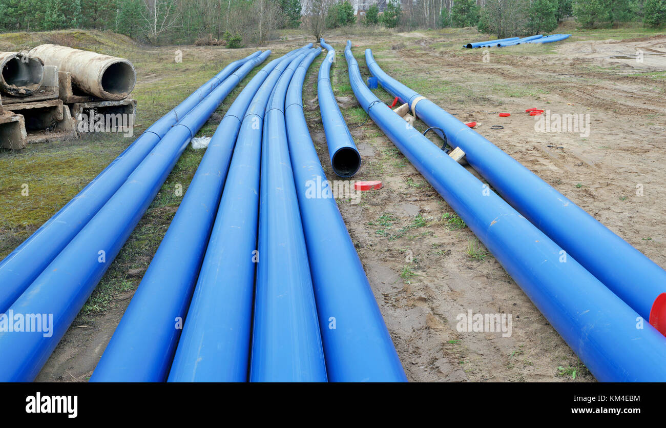 Long blue plastic sewer pipes in the wood. Soon here construction of ...