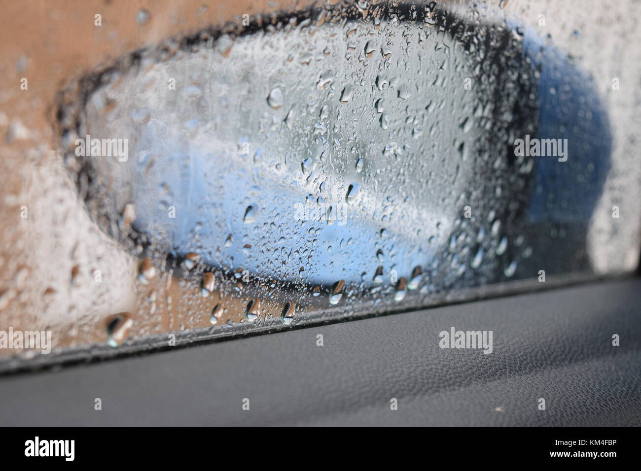 View through a rain covered car window, the focus is on the rain drops ...