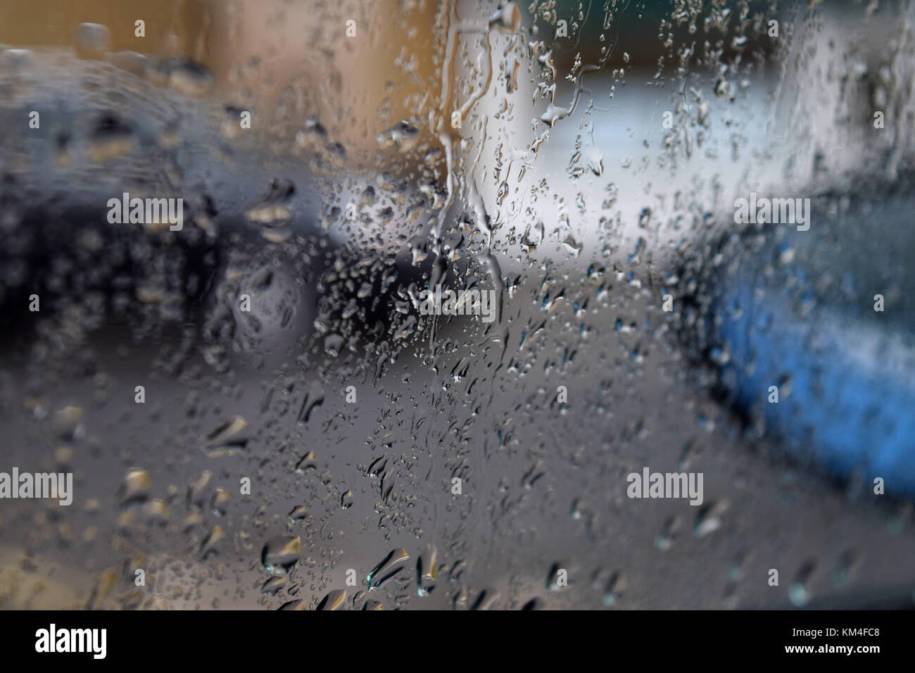 View through a rain covered car window, the focus is on the rain drops ...