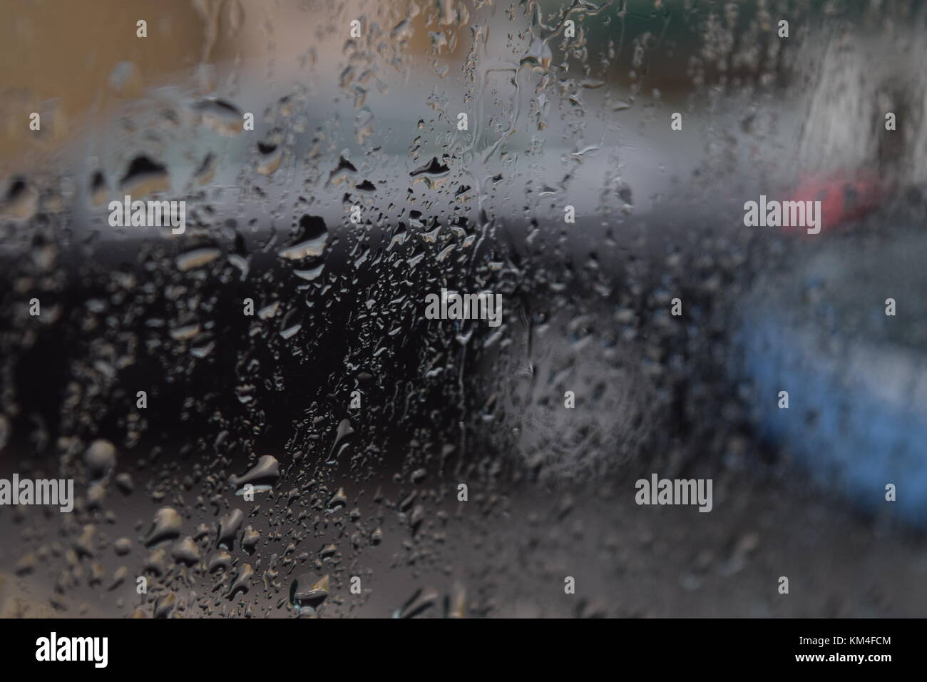View through a rain covered car window, the focus is on the rain drops ...