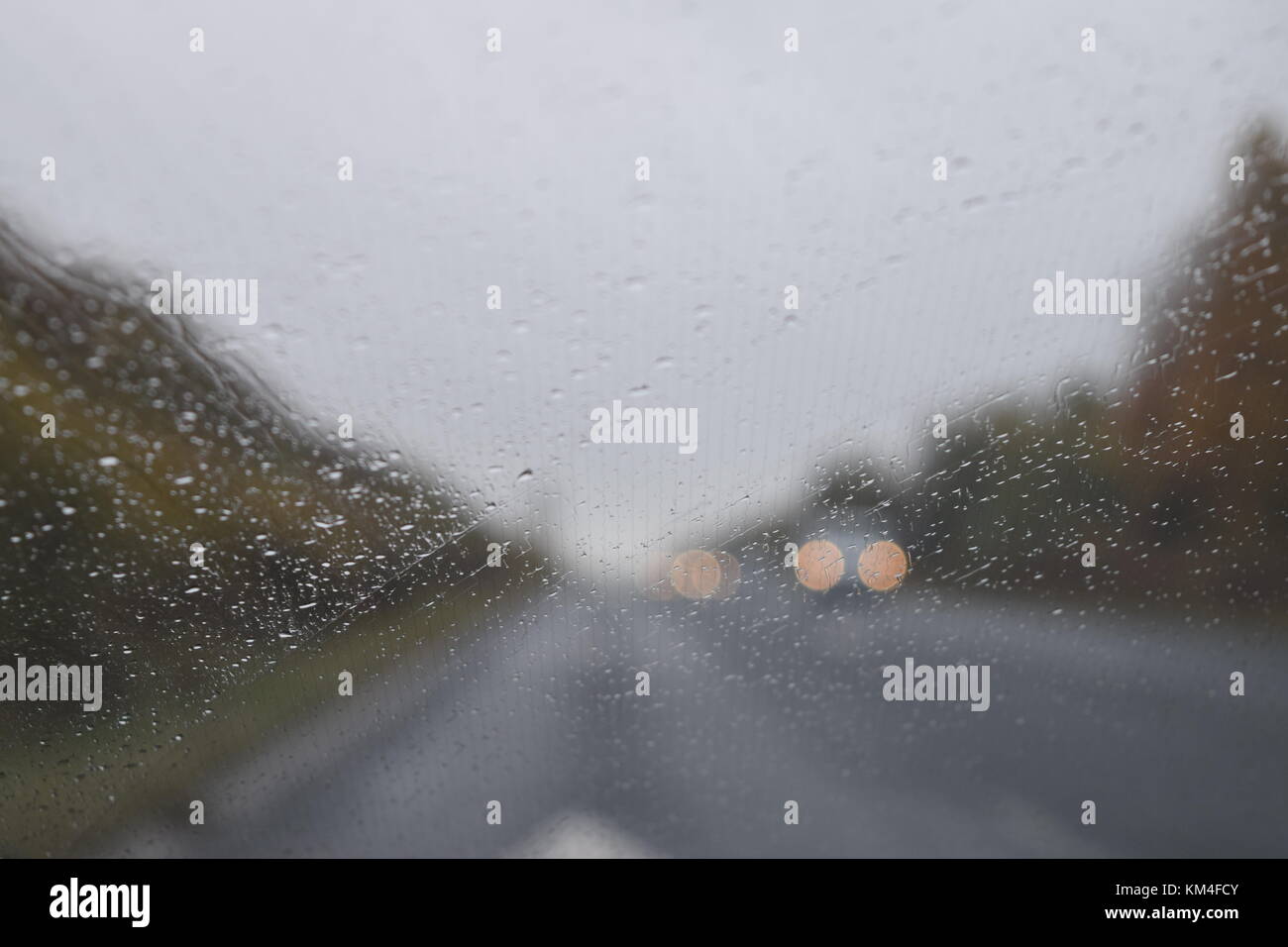 View through a rain covered car window, the focus is on the rain drops ...