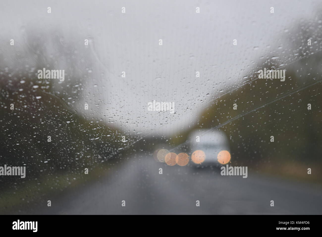 View through a rain covered car window, the focus is on the rain drops ...