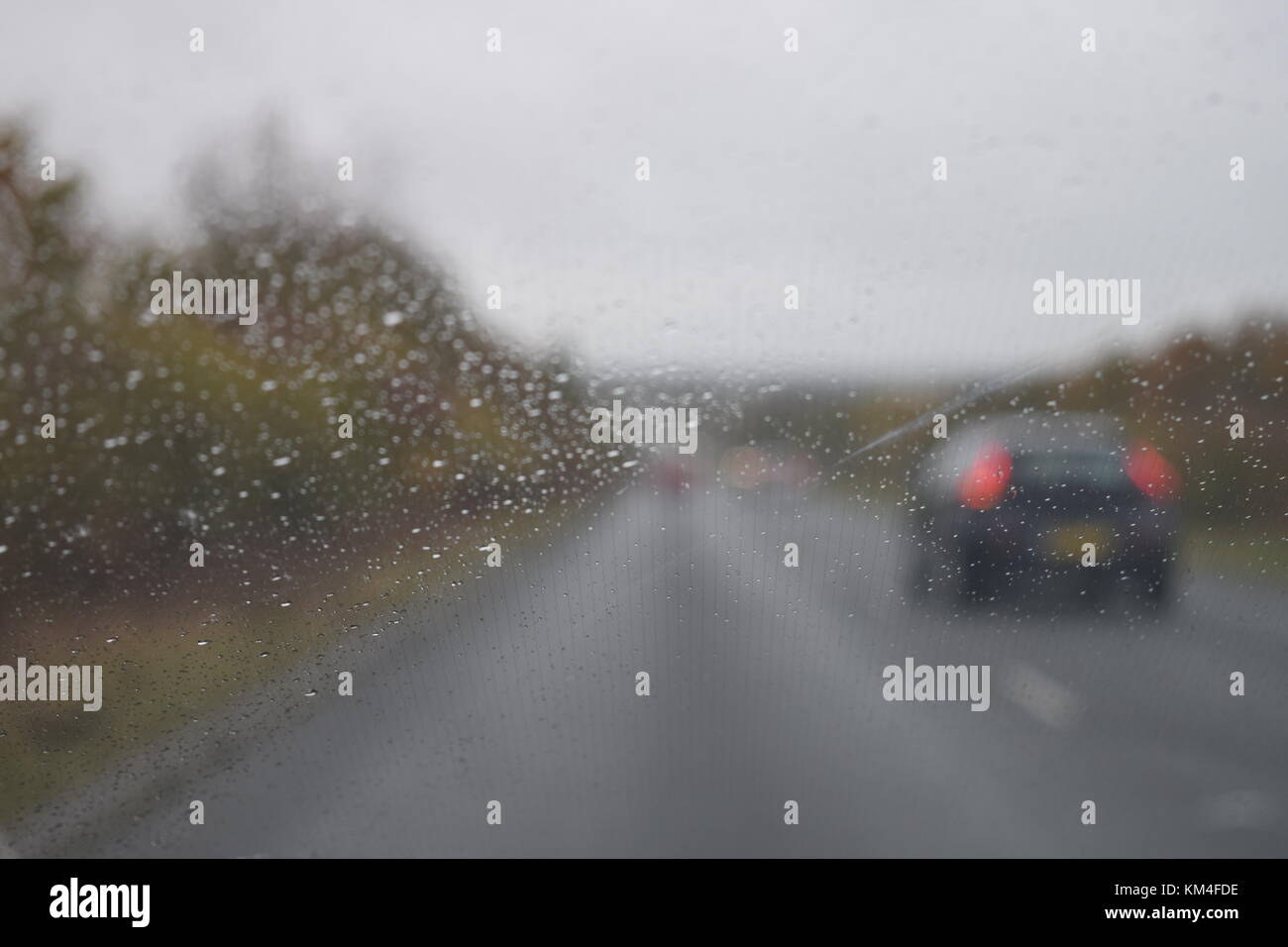 View through a rain covered car window, the focus is on the rain drops ...