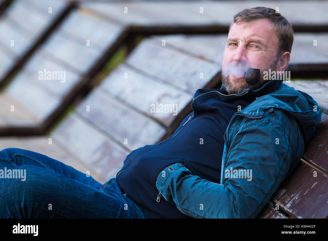 Young man smoking tobacco pipe in autumn park Stock Photo - Alamy