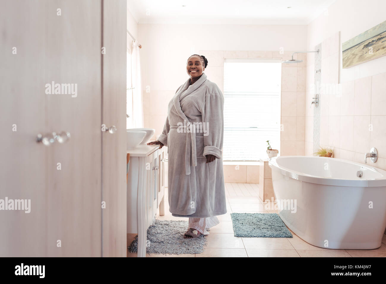 Smiling African woman wearing a robe standing in her bathroom Stock ...