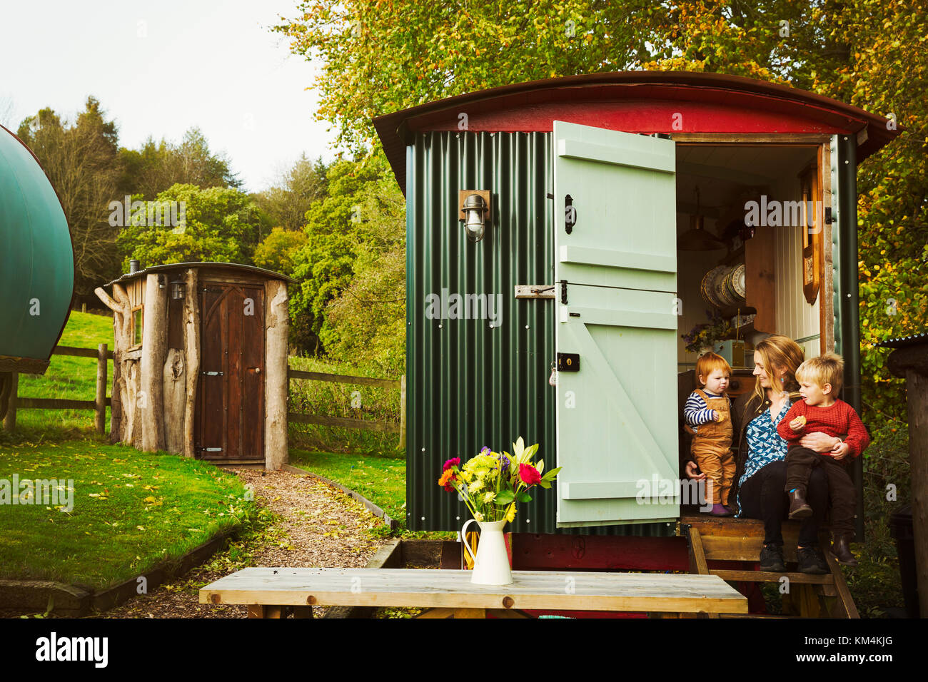 A shepherd's hut with open door beside a path to a small rustic shed ...