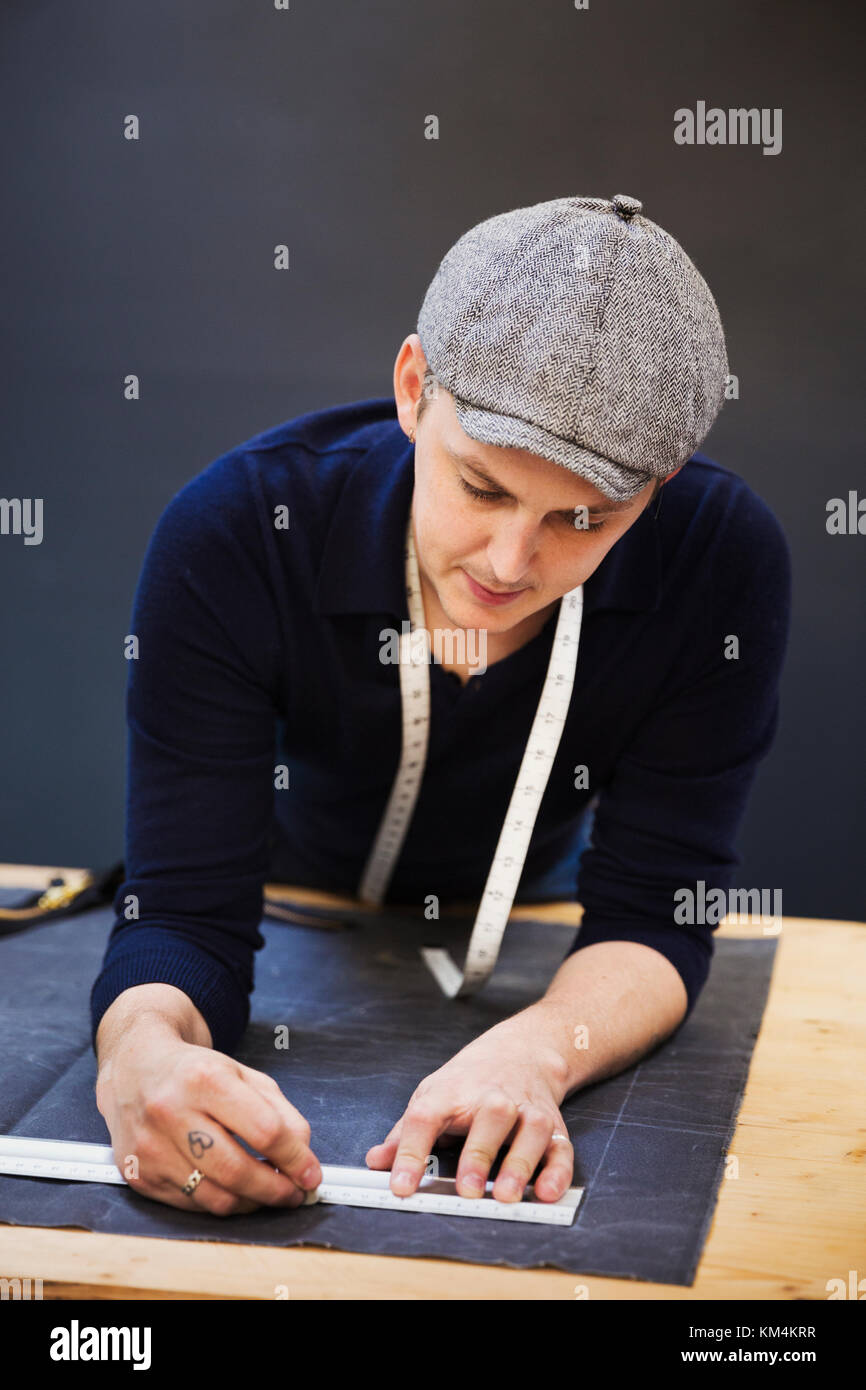 A man measuring with a ruler and marking up with chalk piece of grey ...