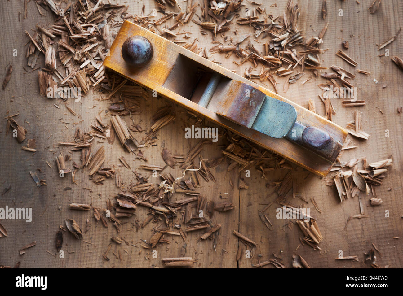 A wood plane on the surface of a piece of wood, shavings scattered ...