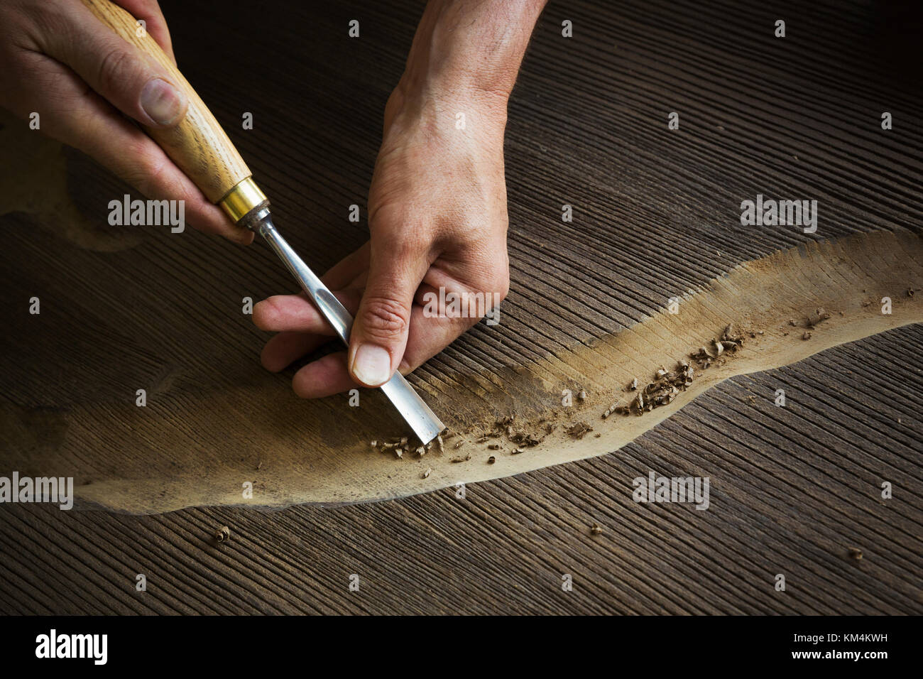 A craftsman using a chisel to carve out a deep groove in a piece of ...