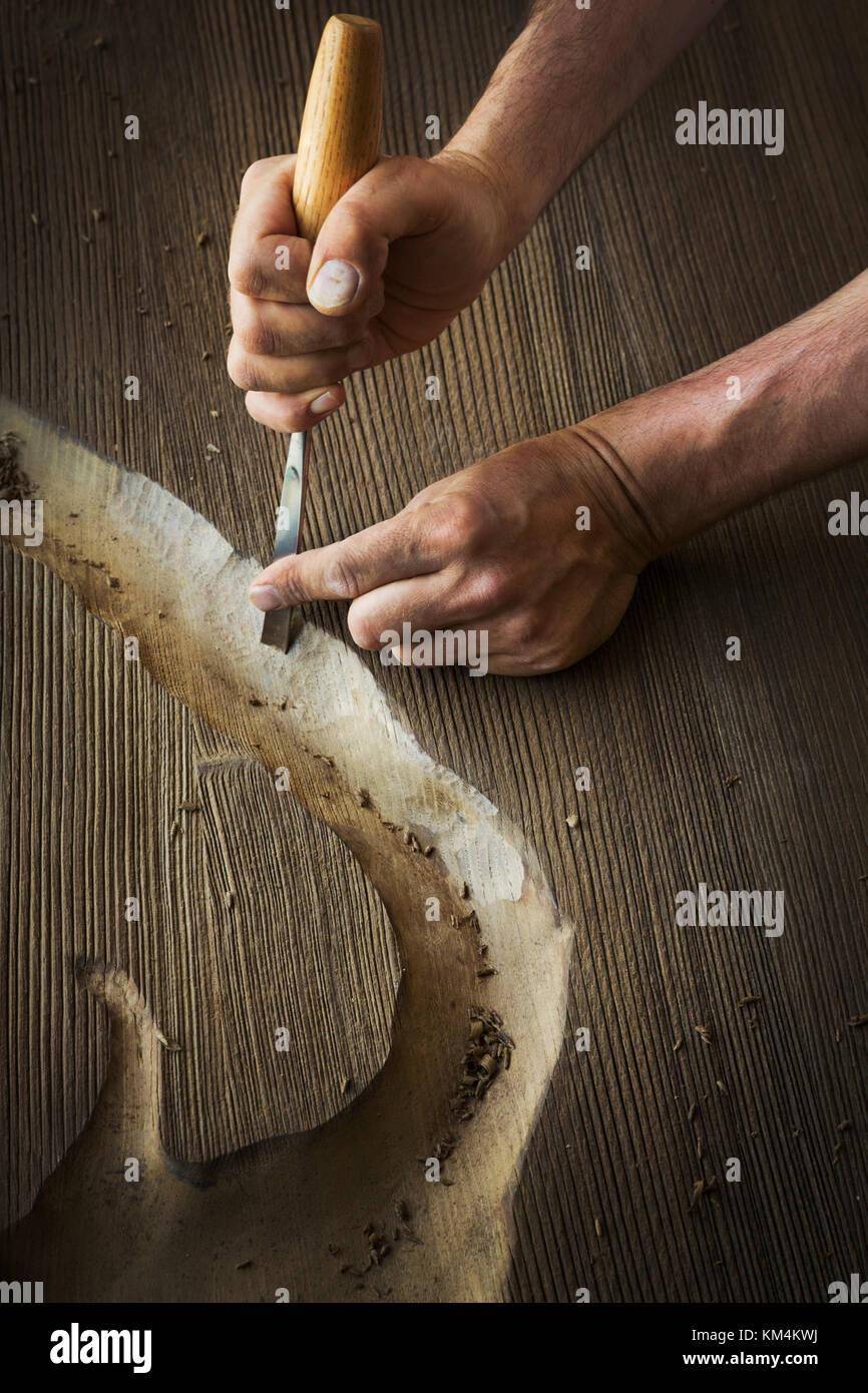 A craftsman using a chisel to carve out a deep groove in a piece of ...