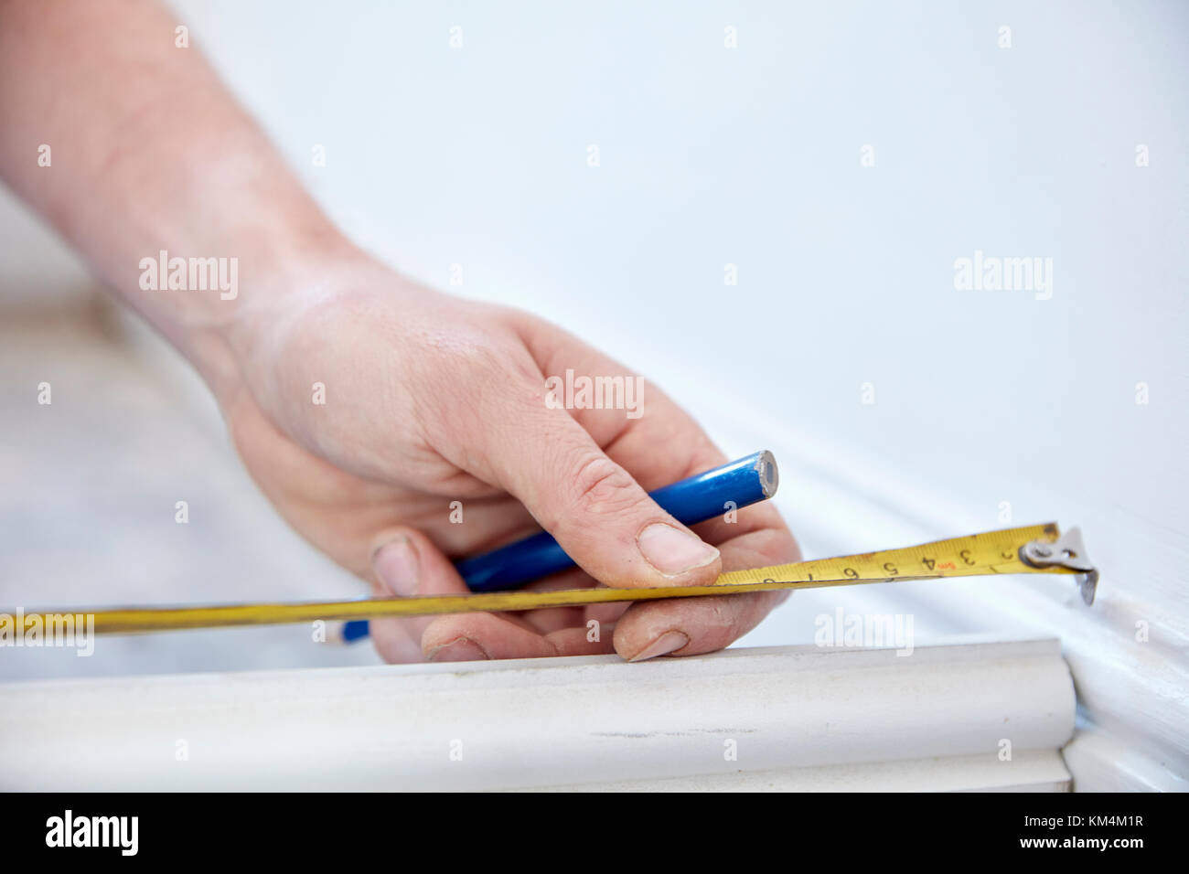 A man using a steel measuring tape, to measure, holding a small pencil ...