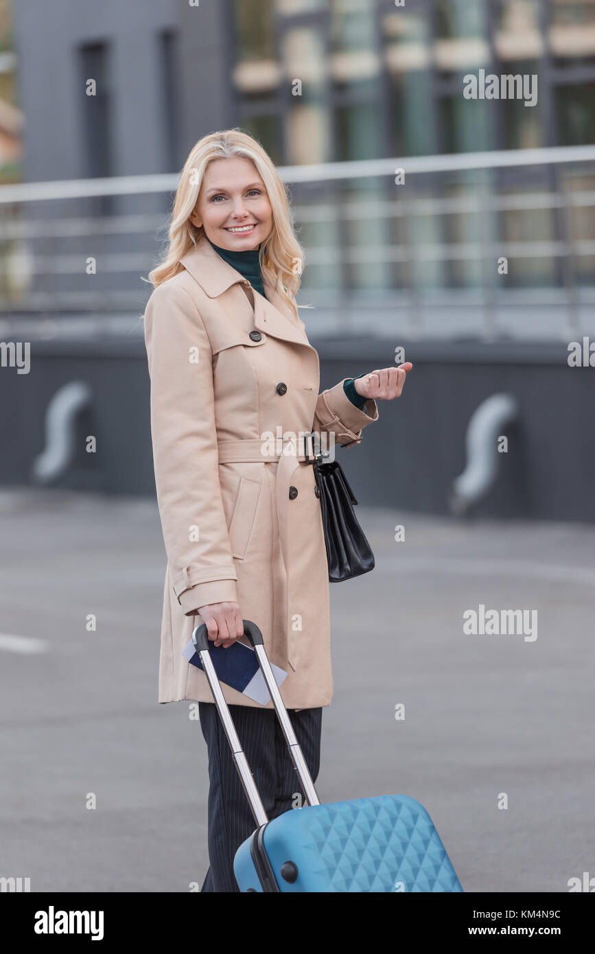 woman in trench coat with luggage Stock Photo - Alamy