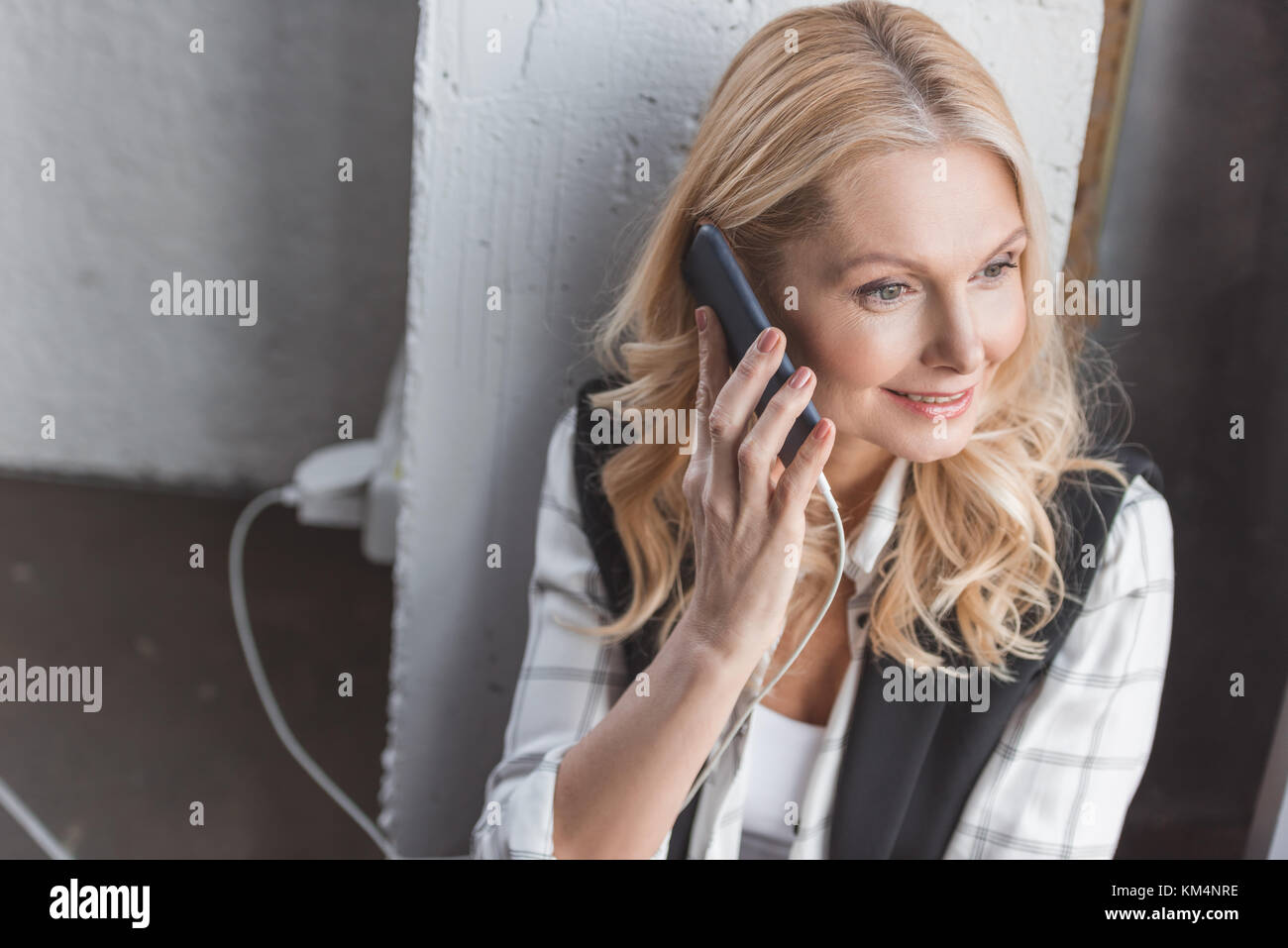 high angle view of businesswoman charging smartphone and making call while sitting on floor in ...