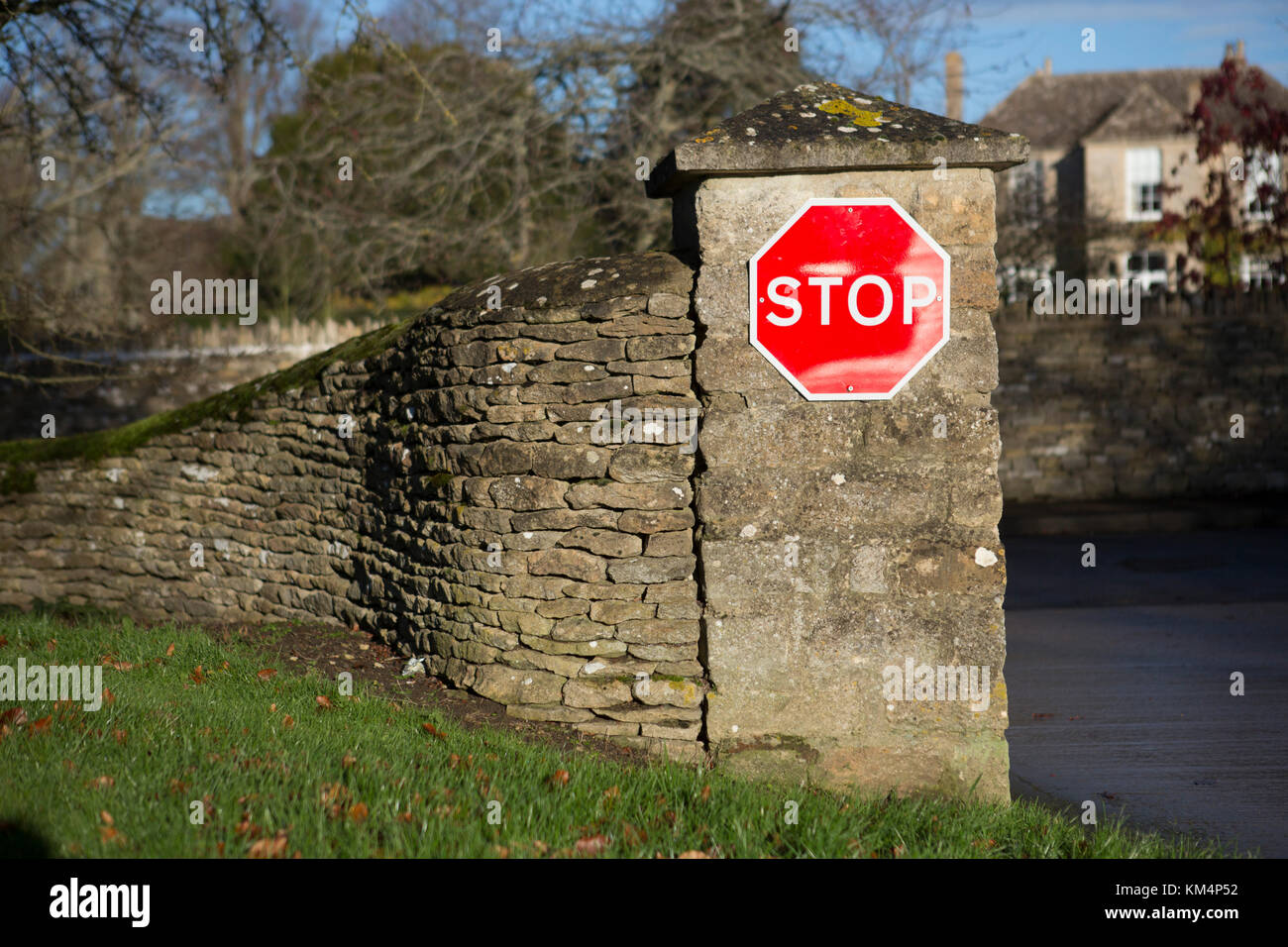 A large red and white stop sign on an old dry stone wall in the ...