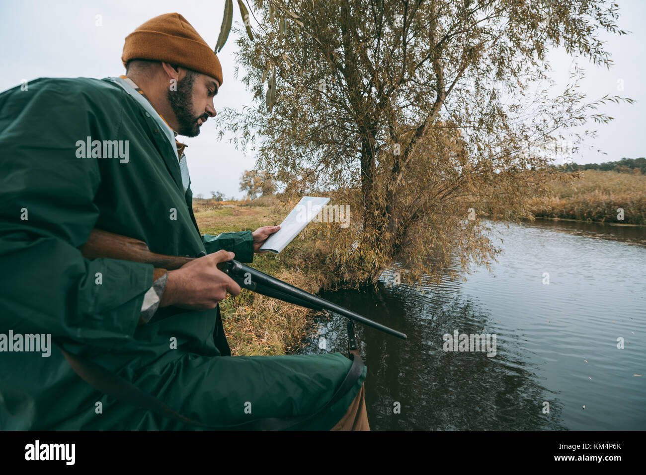 hunter standing with gun and looking at map Stock Photo - Alamy