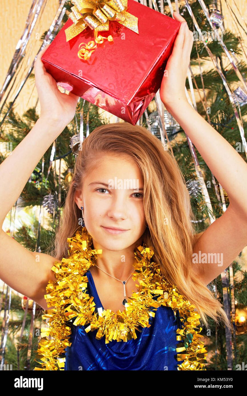 Happy teen girl holding a present over her head. In the background is a ...