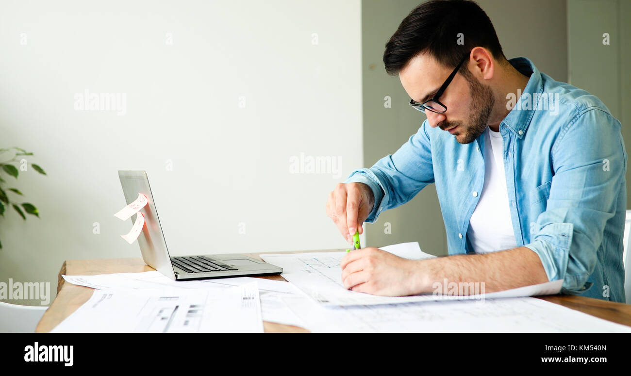 Architect working on plans at home office table Stock Photo - Alamy