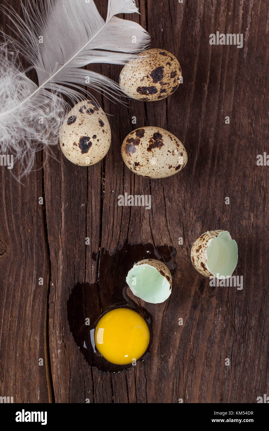Top view on broken quail egg with the leaked yolk on old wooden table ...