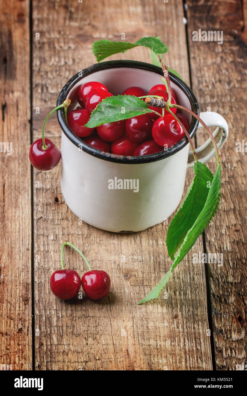 Vintage mug of fresh cherries with leaves on old wooden table Stock ...