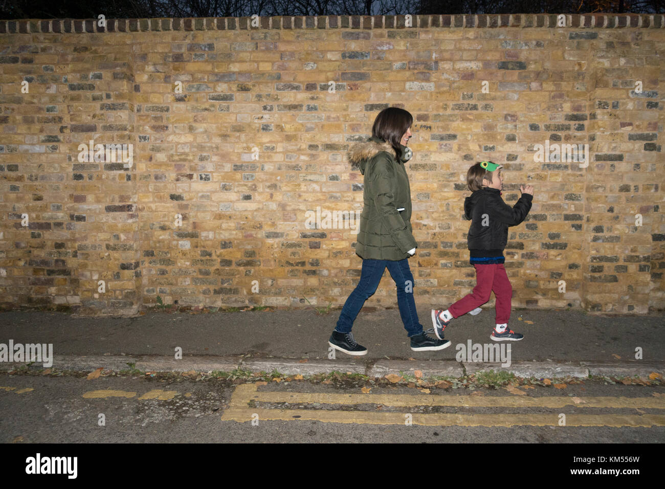 Mother and son walk past a wall Stock Photo - Alamy