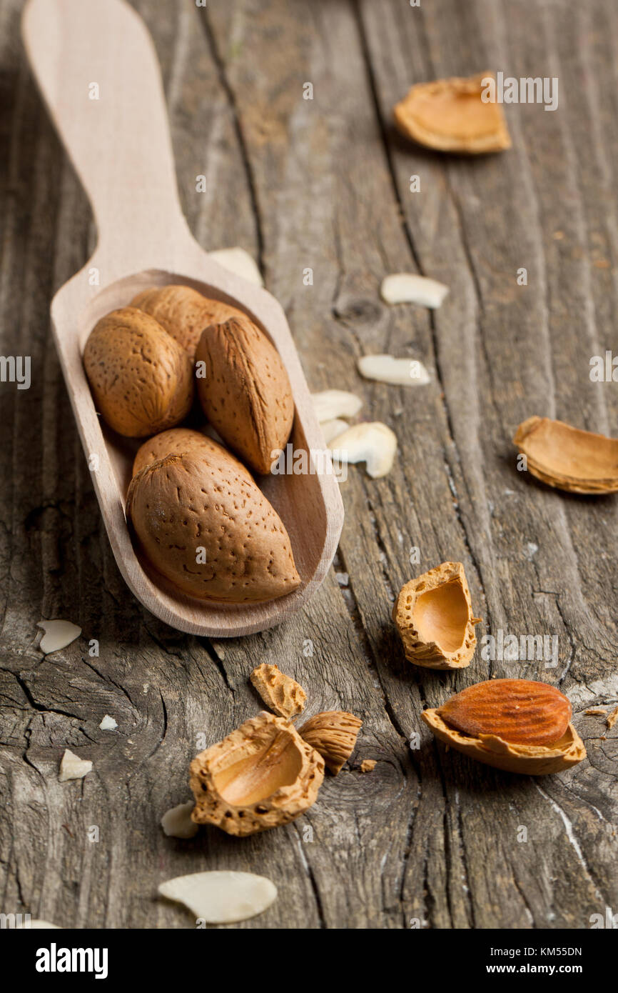 Whole and chopped almonds on old wooden table Stock Photo - Alamy