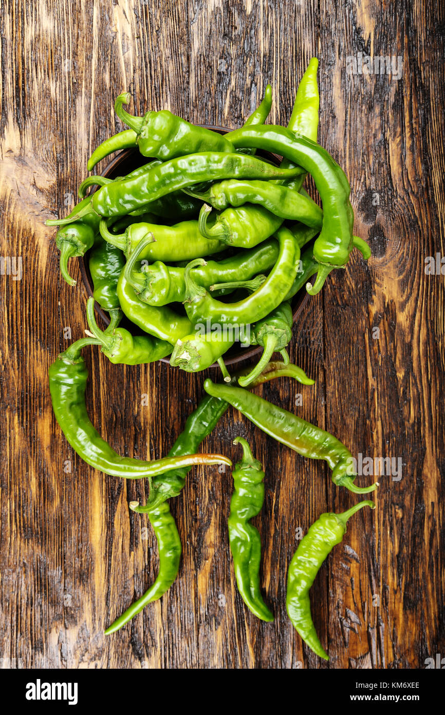 green chili peppers placed in a clay plate on a brown wooden table ...