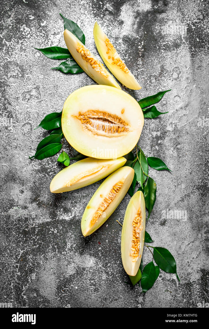 Fresh melon with green leaves. On rustic background Stock Photo - Alamy