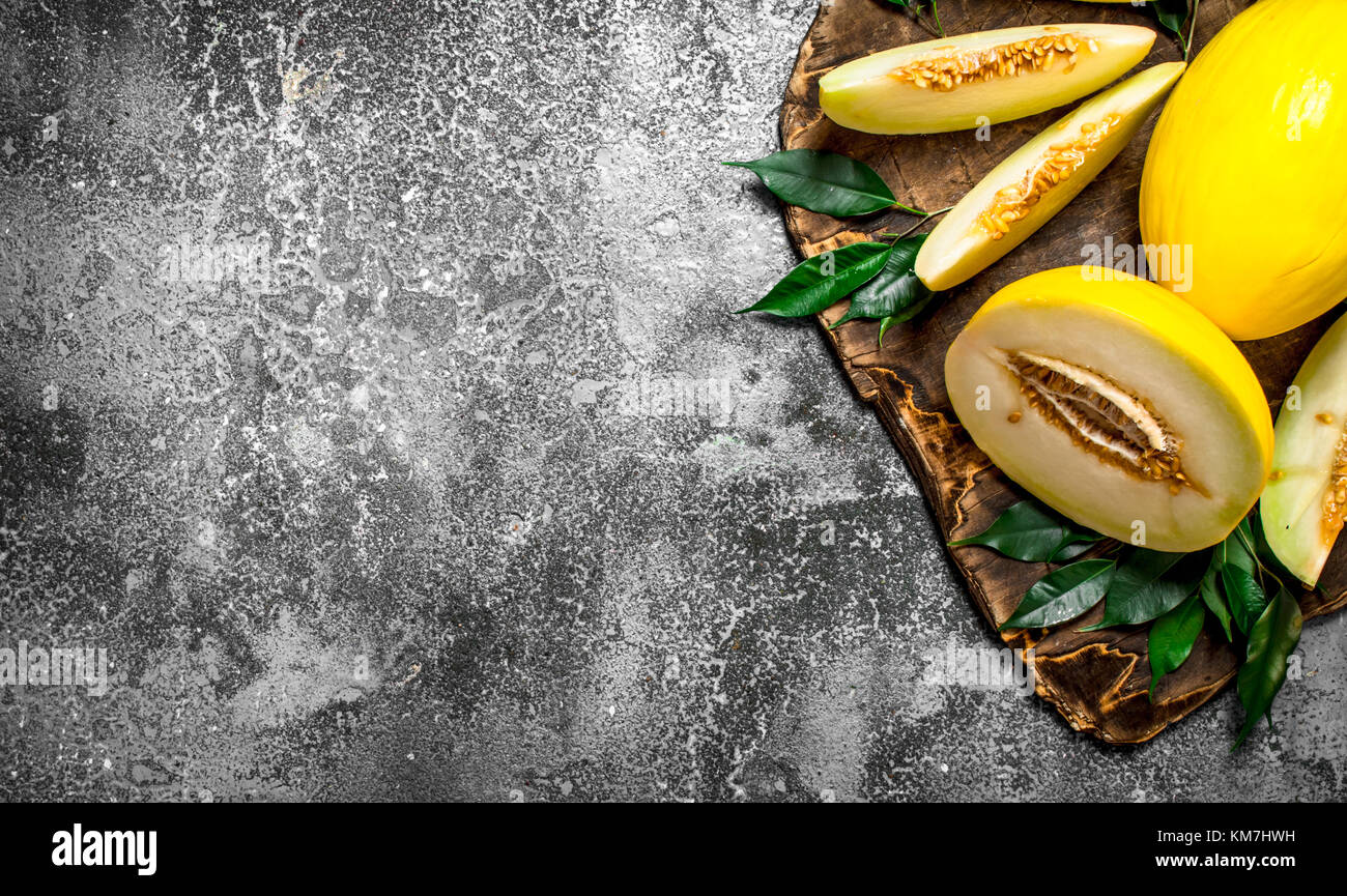 Fresh melon with green leaves. On rustic background Stock Photo - Alamy