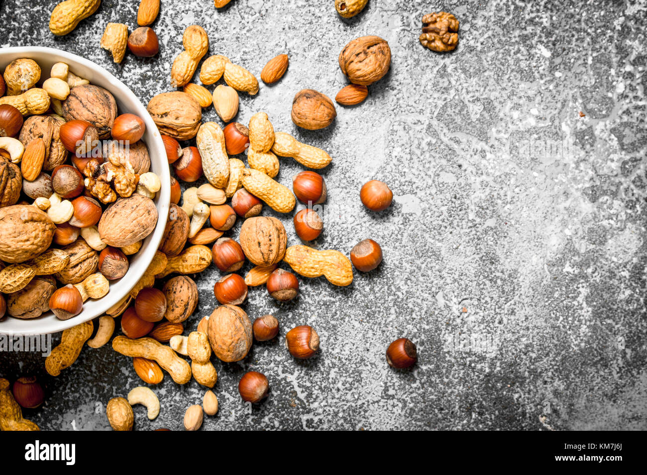 Different nuts in a bowl. On rustic background Stock Photo - Alamy