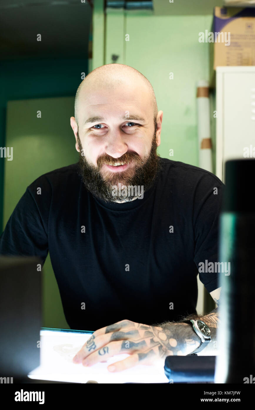 London, UK, Tattoo artist at work in his local business studio ...