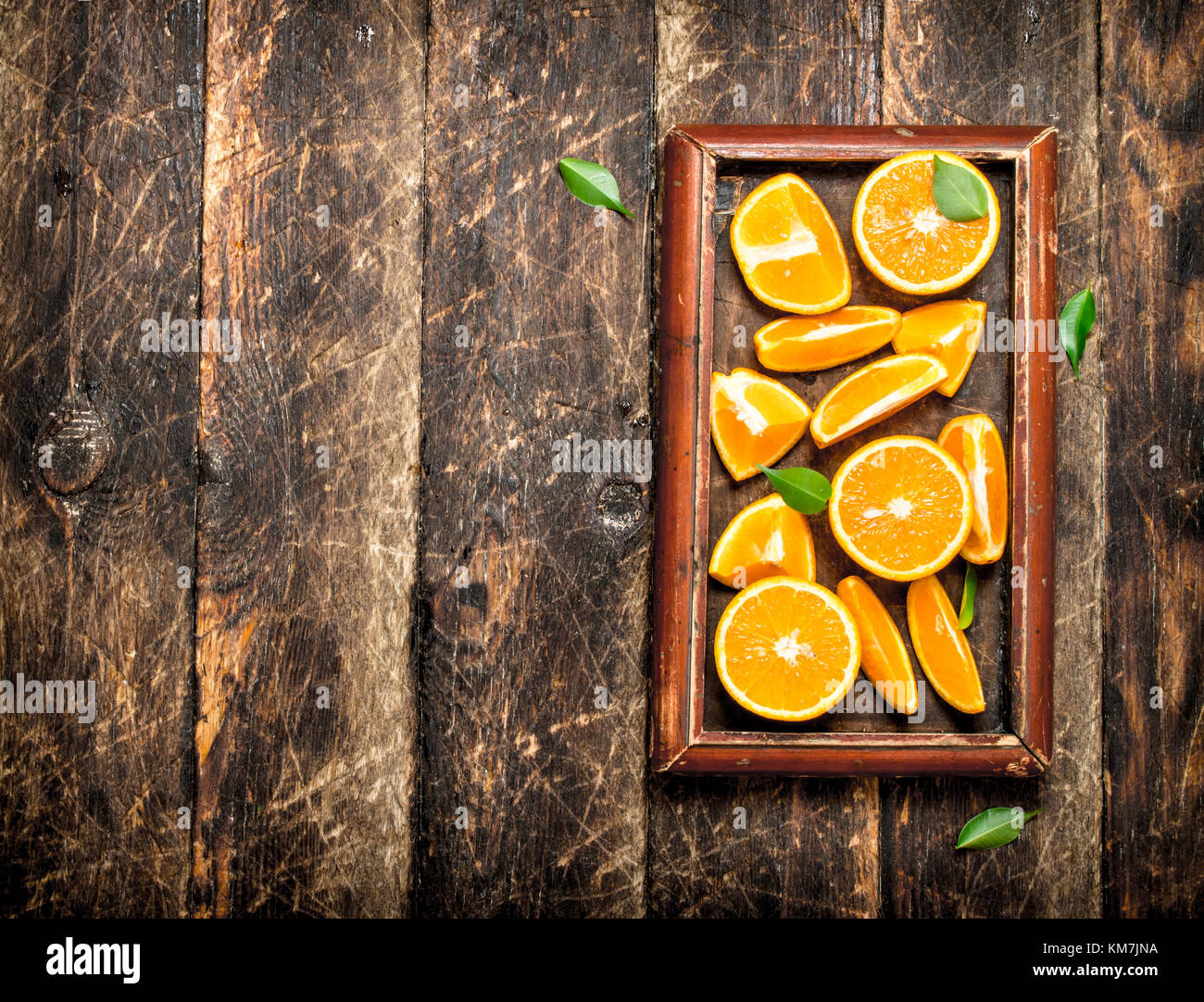 Fresh slices of oranges in the old tray. On wooden background Stock ...
