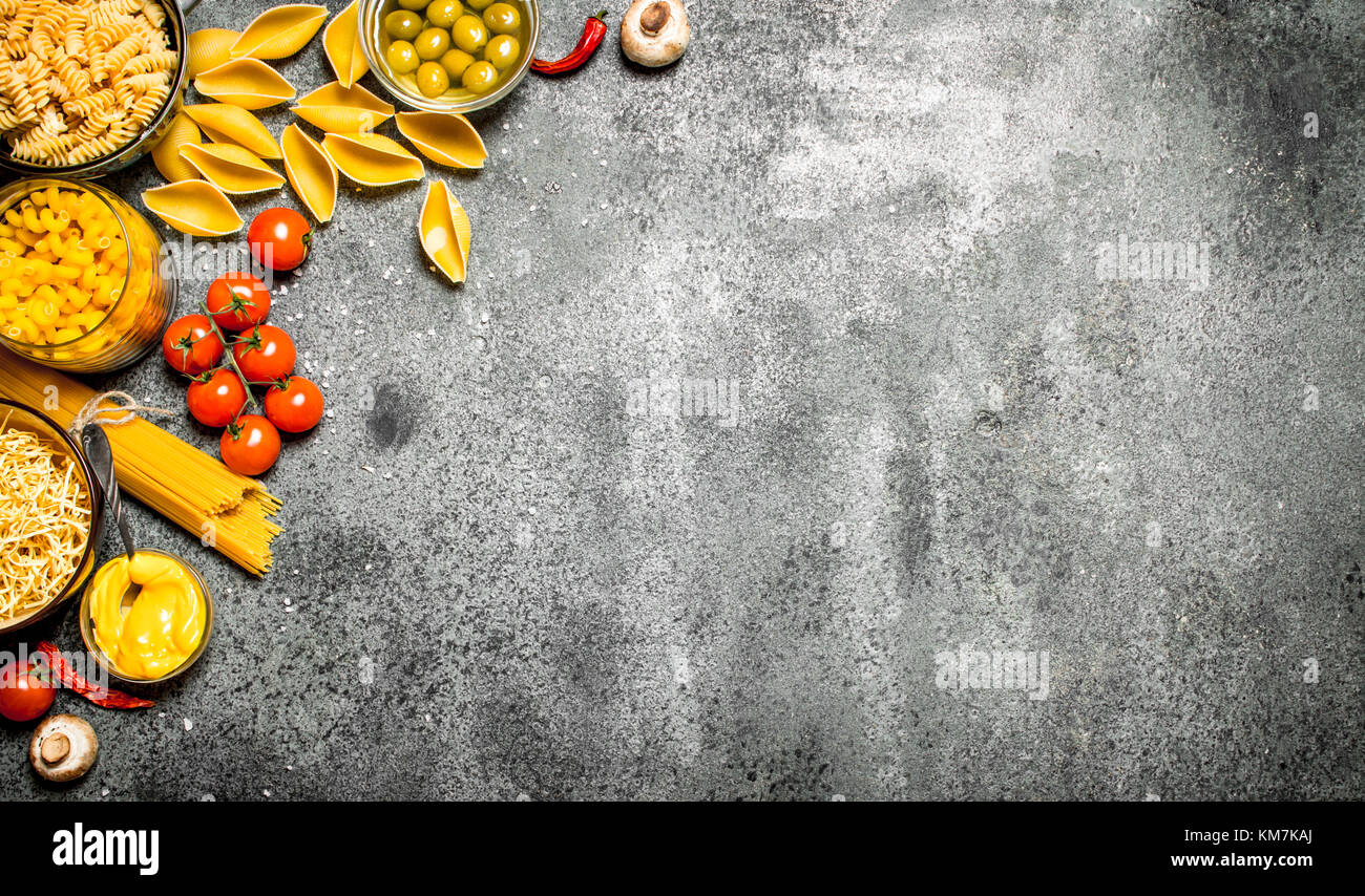 Pasta background. Various pasta with spices and vegetables. On rustic ...