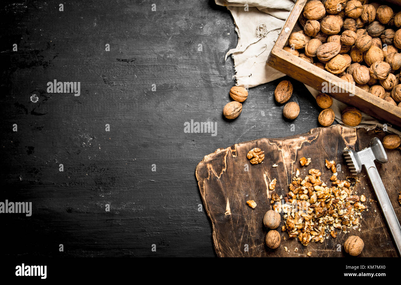 Crushed walnuts with a hammer on the old Board. On a black chalkboard ...