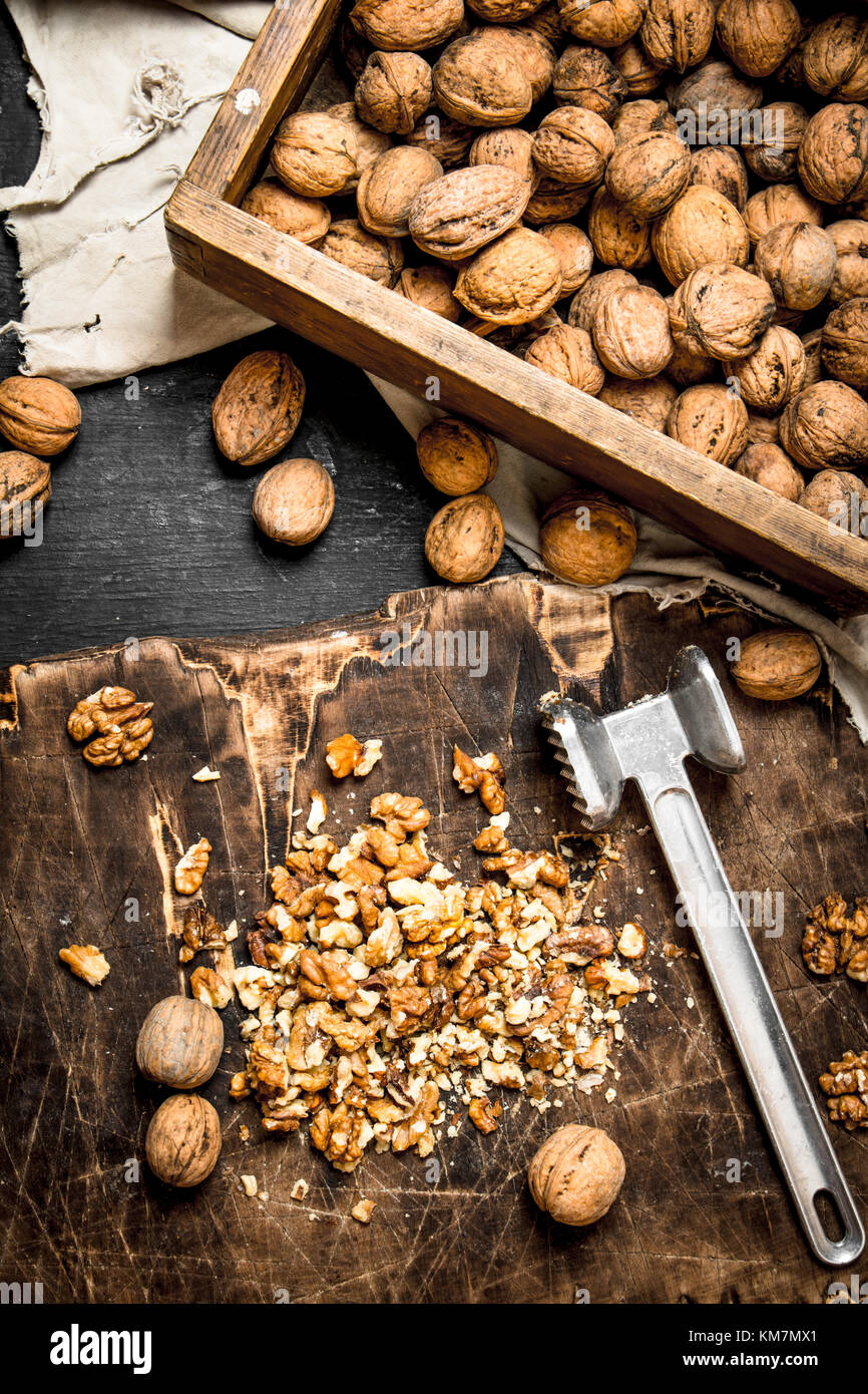 Crushed walnuts with a hammer on the old Board. On a black chalkboard ...