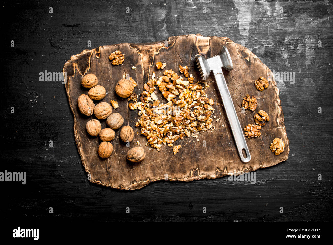 Crushed walnuts with a hammer on the old Board. On a black chalkboard ...