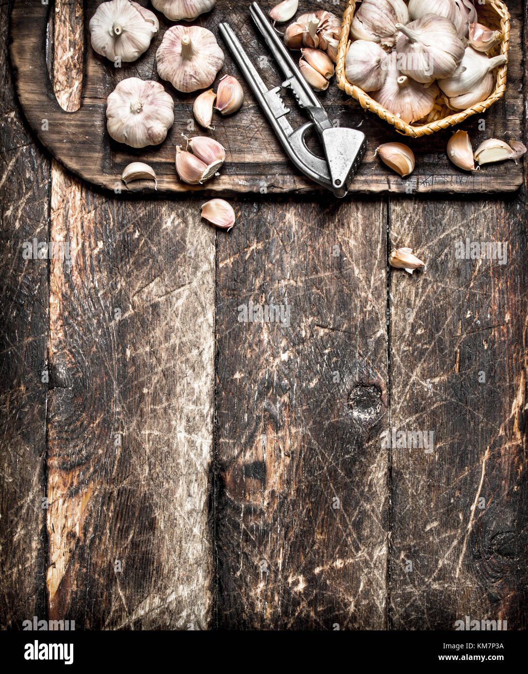 Fragrant garlic with a press tool on a wooden Board. On rustic ...
