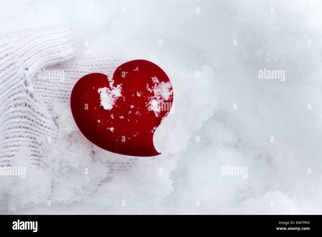 Red freeze Heart in cozy arms on snow winter background . Save love ...