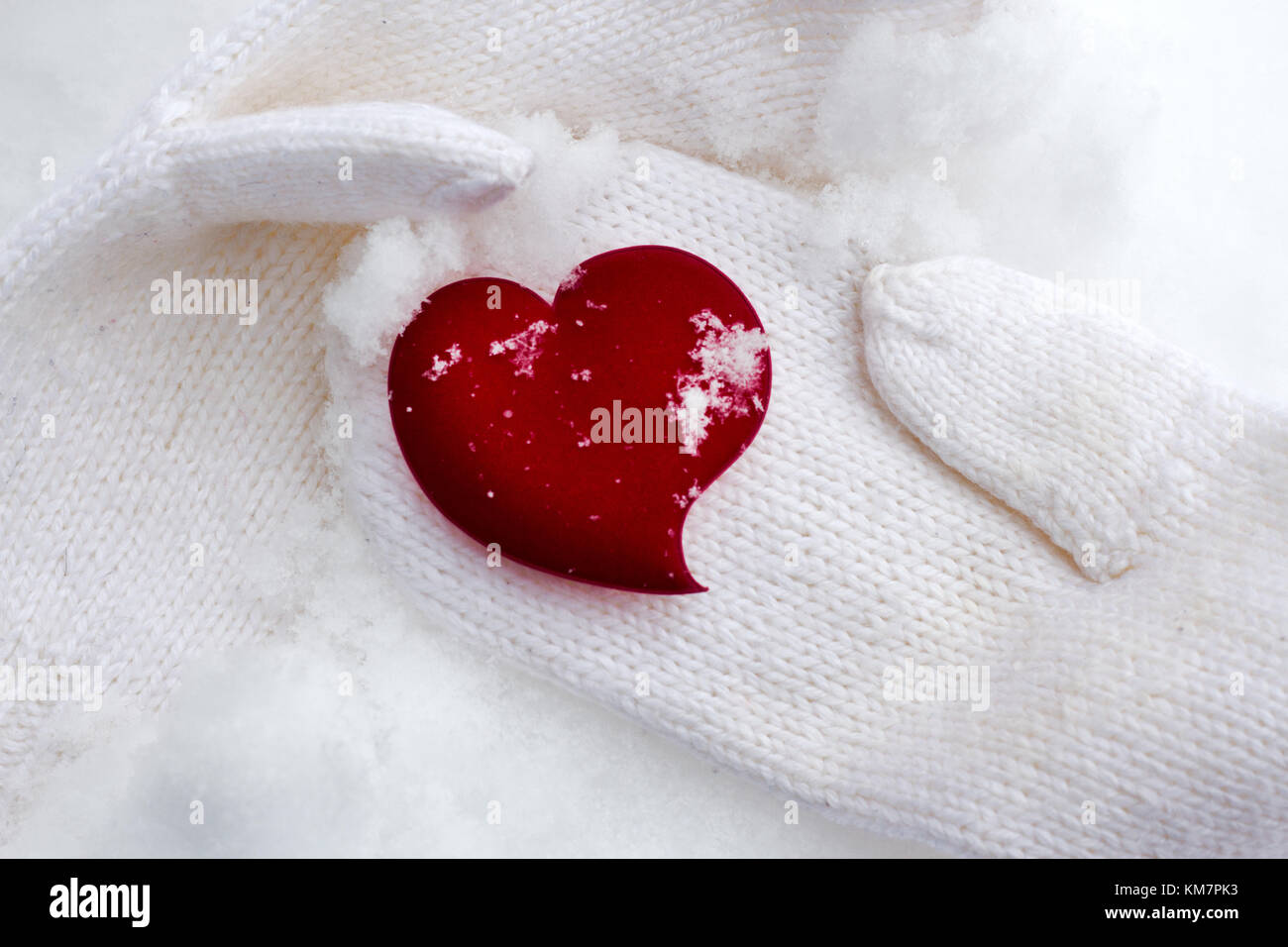 Red freeze Heart in cozy arms on snow winter background . Save love ...