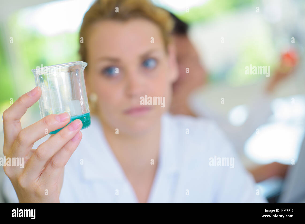Lady looking at liquid in glass beaker Stock Photo - Alamy