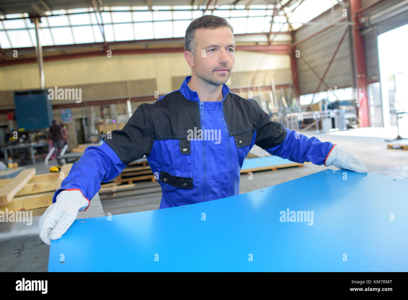 Workman holding sheet of metal Stock Photo - Alamy